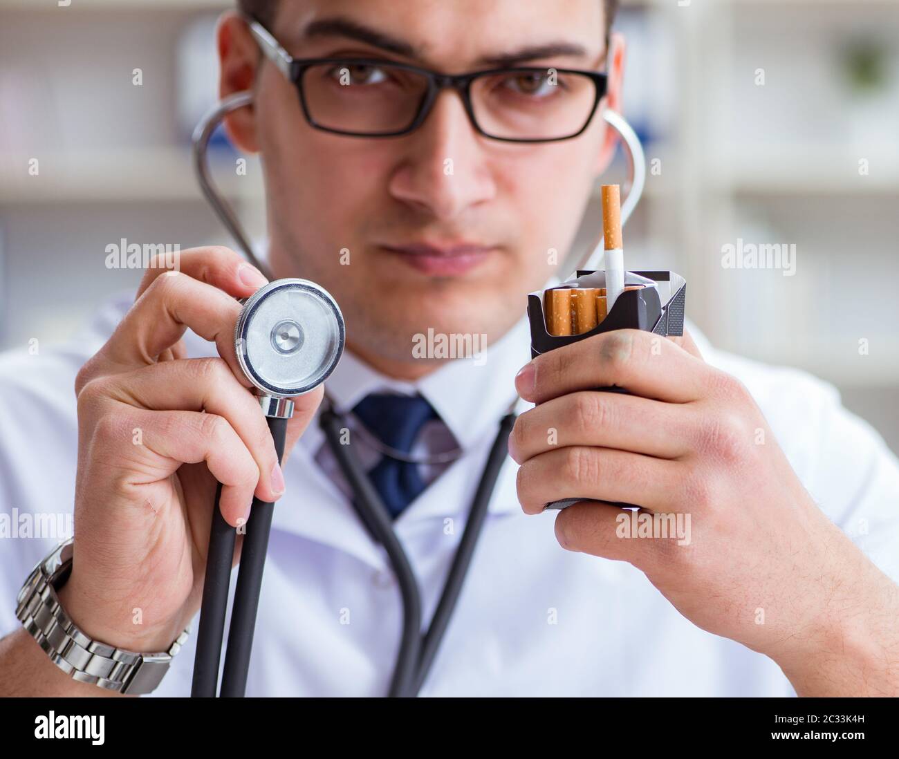 Male doctor in anti-smoking conceptwithcigarette pack Stock Photo - Alamy