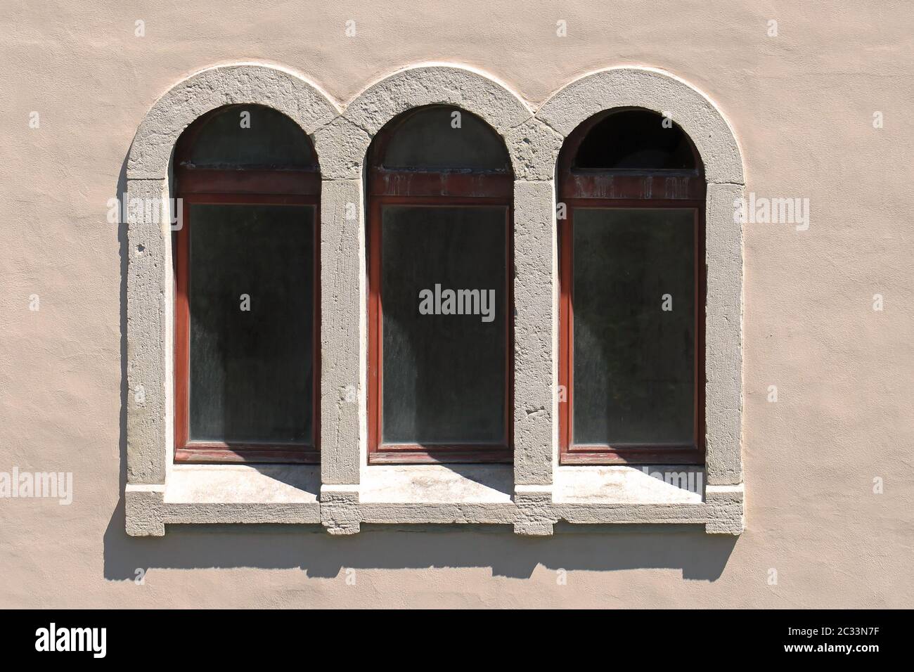 Old retro closed glass windows with arches on stone facade Stock Photo ...