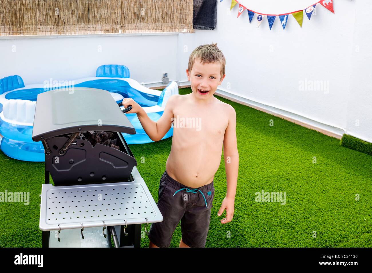 Happy boy in summer in his backyard having a barbecue Stock Photo - Alamy