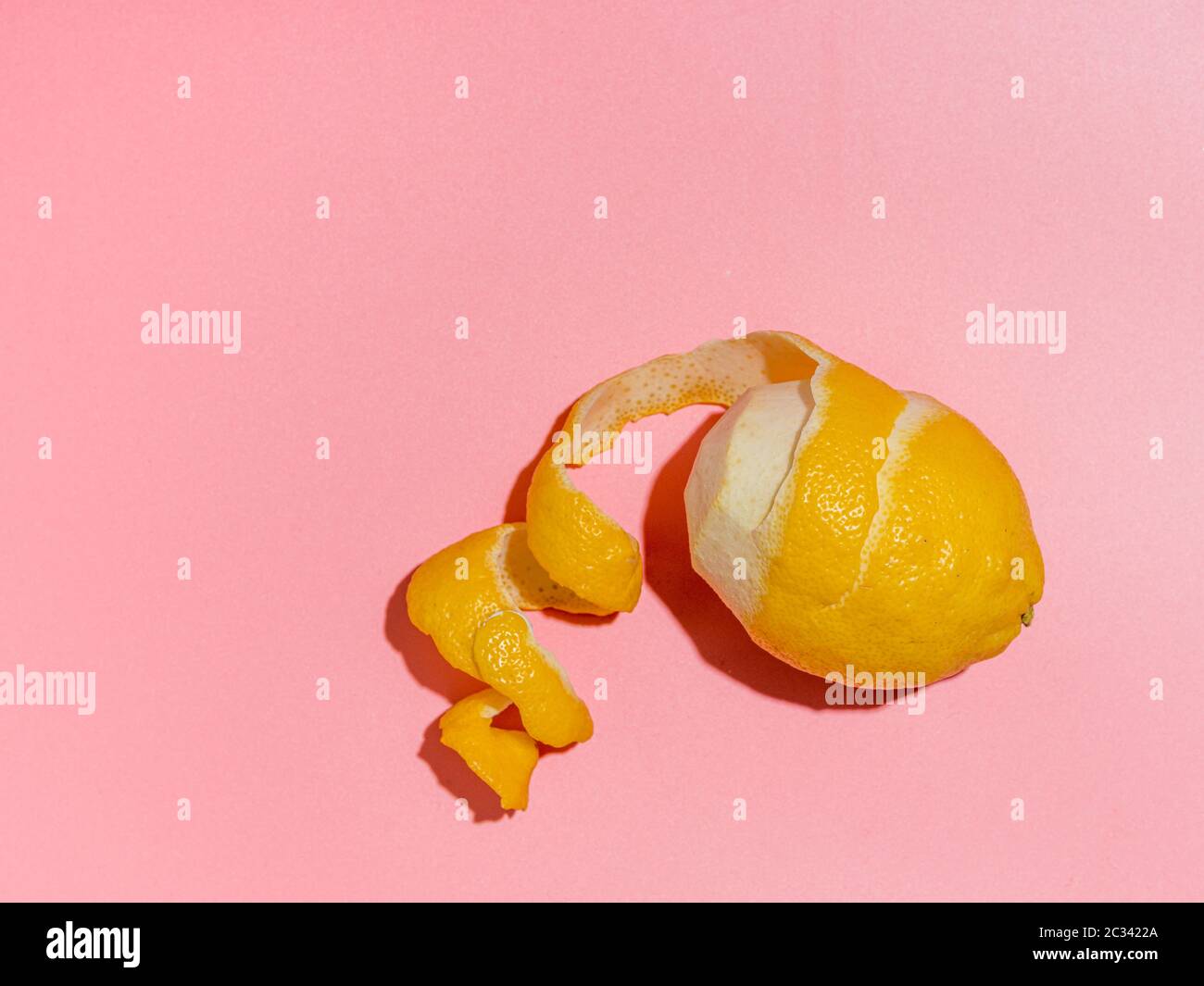Lemon with spiral peeled zest over pink minimalistic background. Lemon ...