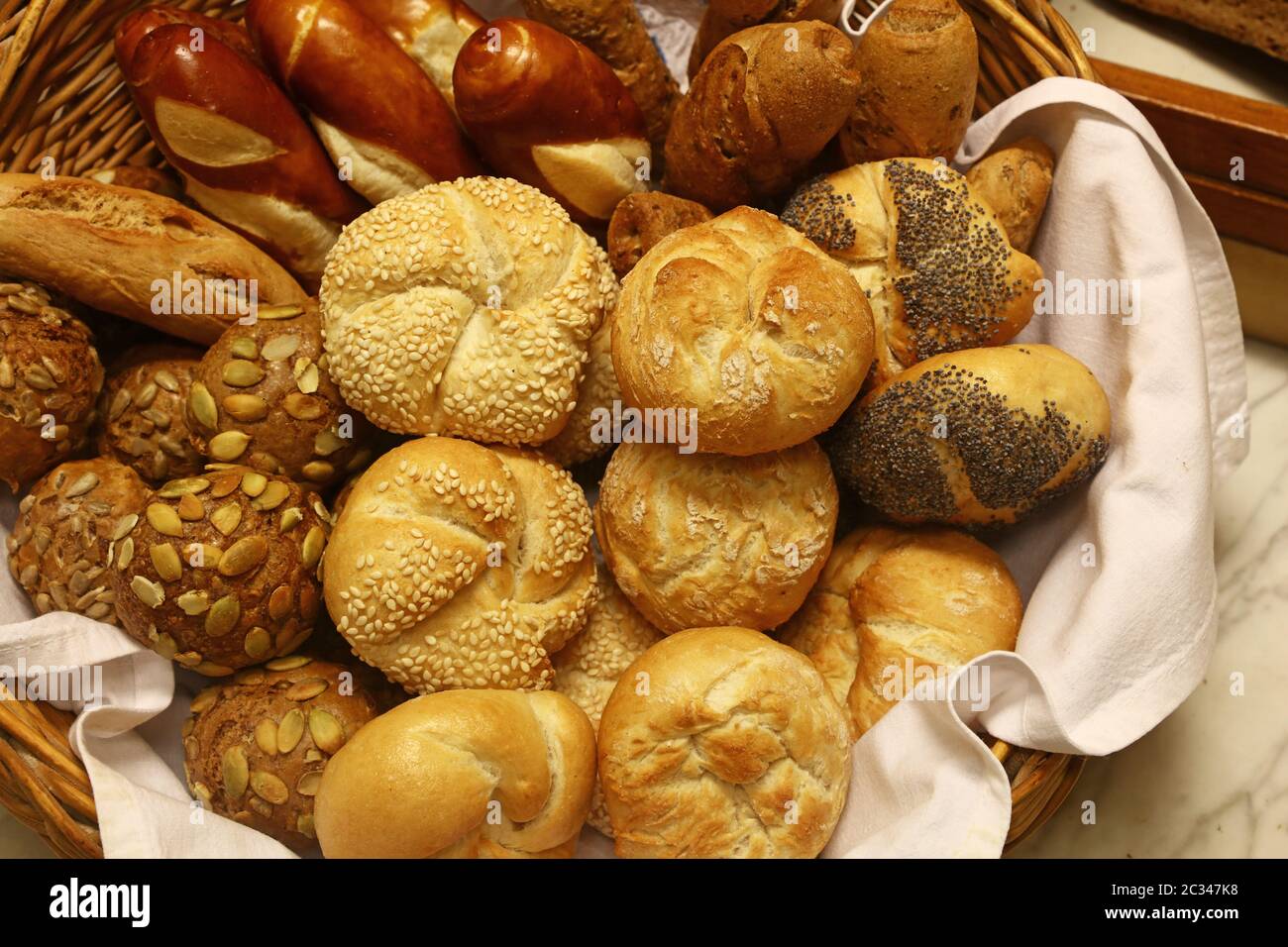 Close up several assorted fresh bread buns in basket on retail display ...