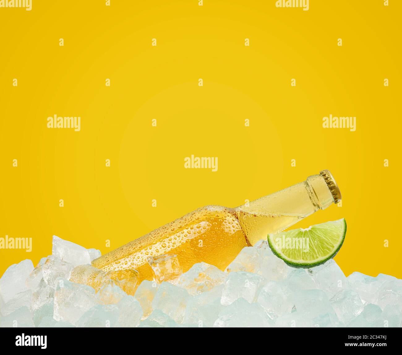 Close up one clear glass bottle of cold lager beer on ice cubes at ...