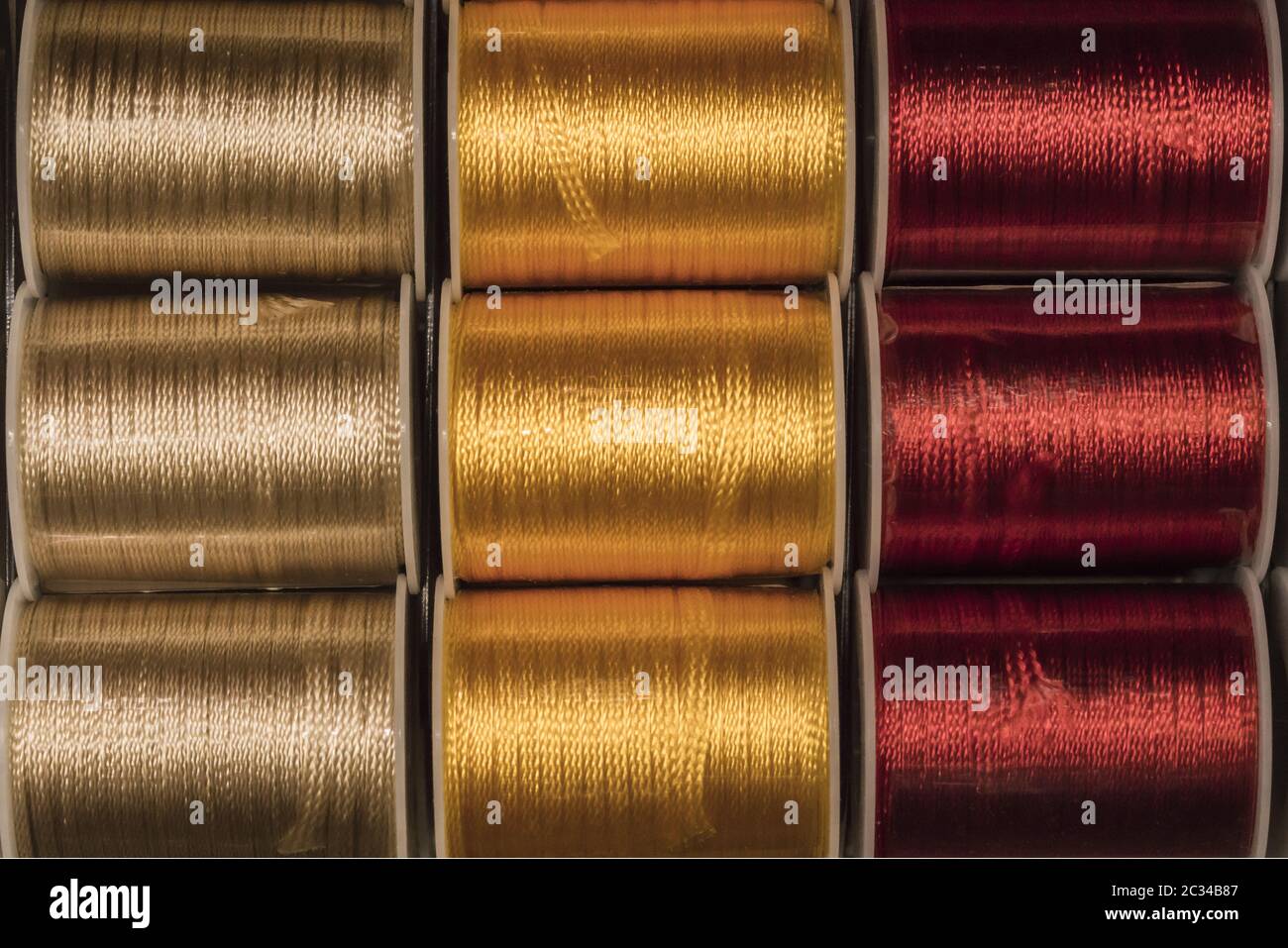 Cutout texture closeup on coils of colored sewing threads gold, yellow ...