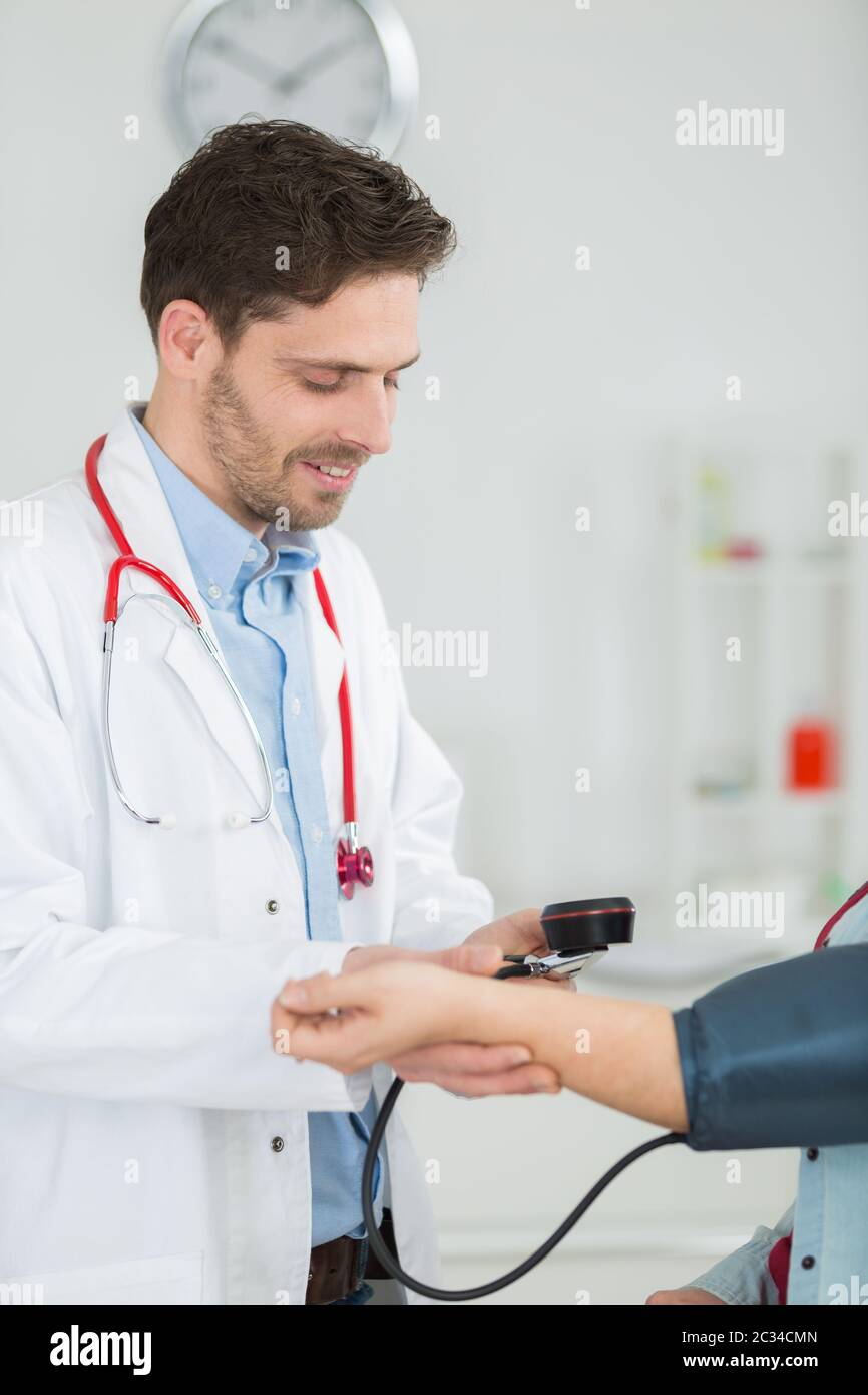 portrait of happy doctor checking patients blood pressure in clinic ...