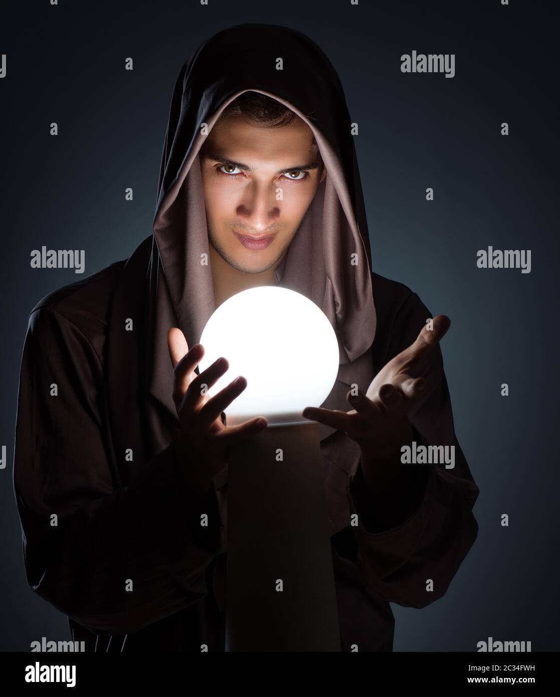 Young wizard with crystal ball in dark room Stock Photo - Alamy