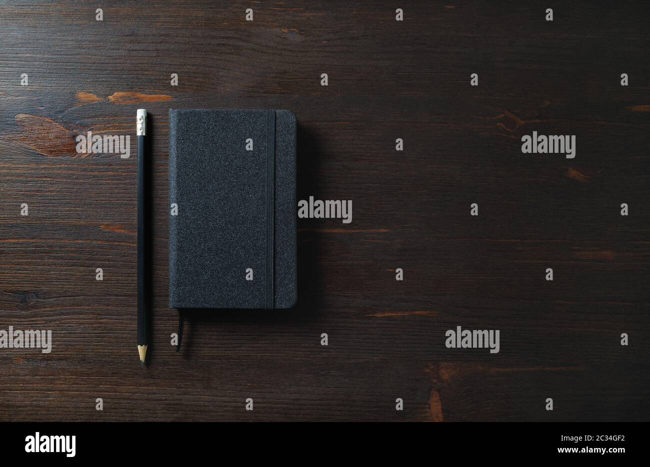 Black notepad and pencil on wood table background. Responsive design ...