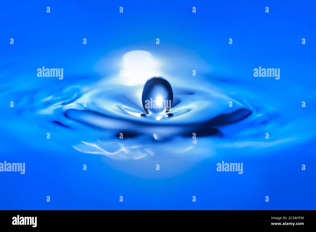 Closeup on drop of water falling in a blue liquid Stock Photo - Alamy