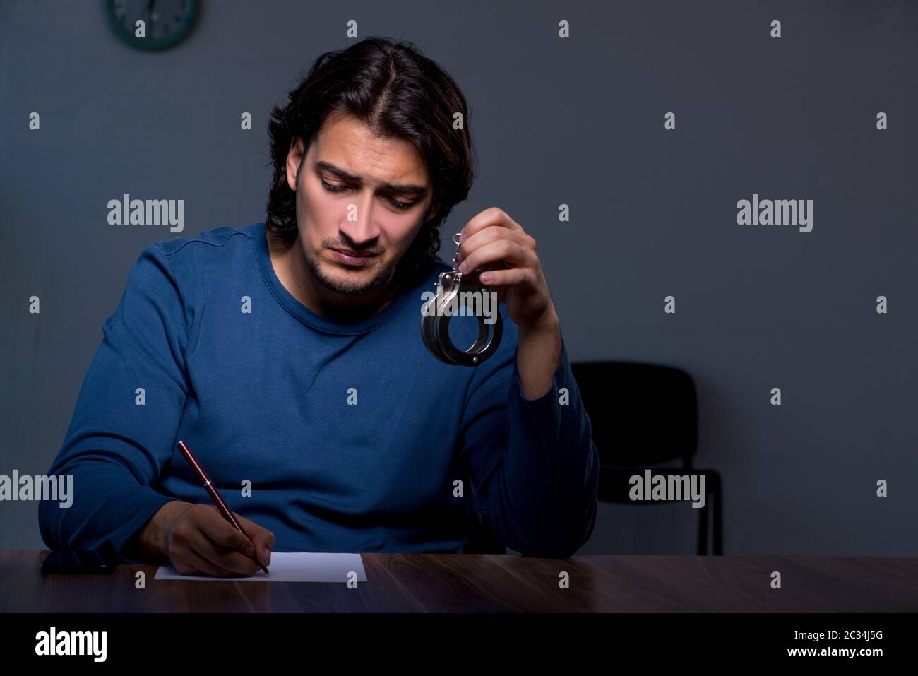 Young convict man sitting in dark room Stock Photo - Alamy
