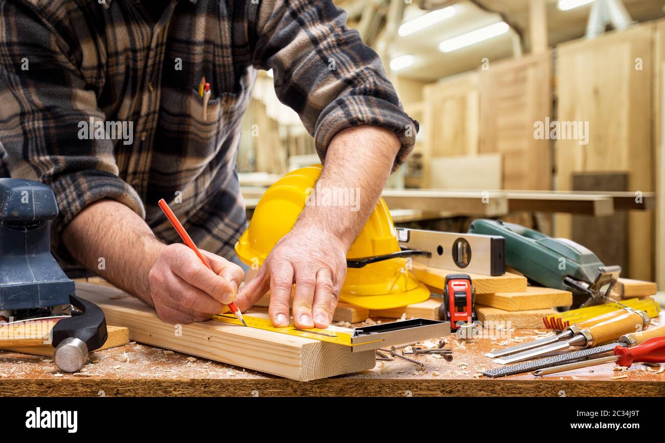 Close-up. Carpenter with pencil and carpenter's square draw the cutting ...