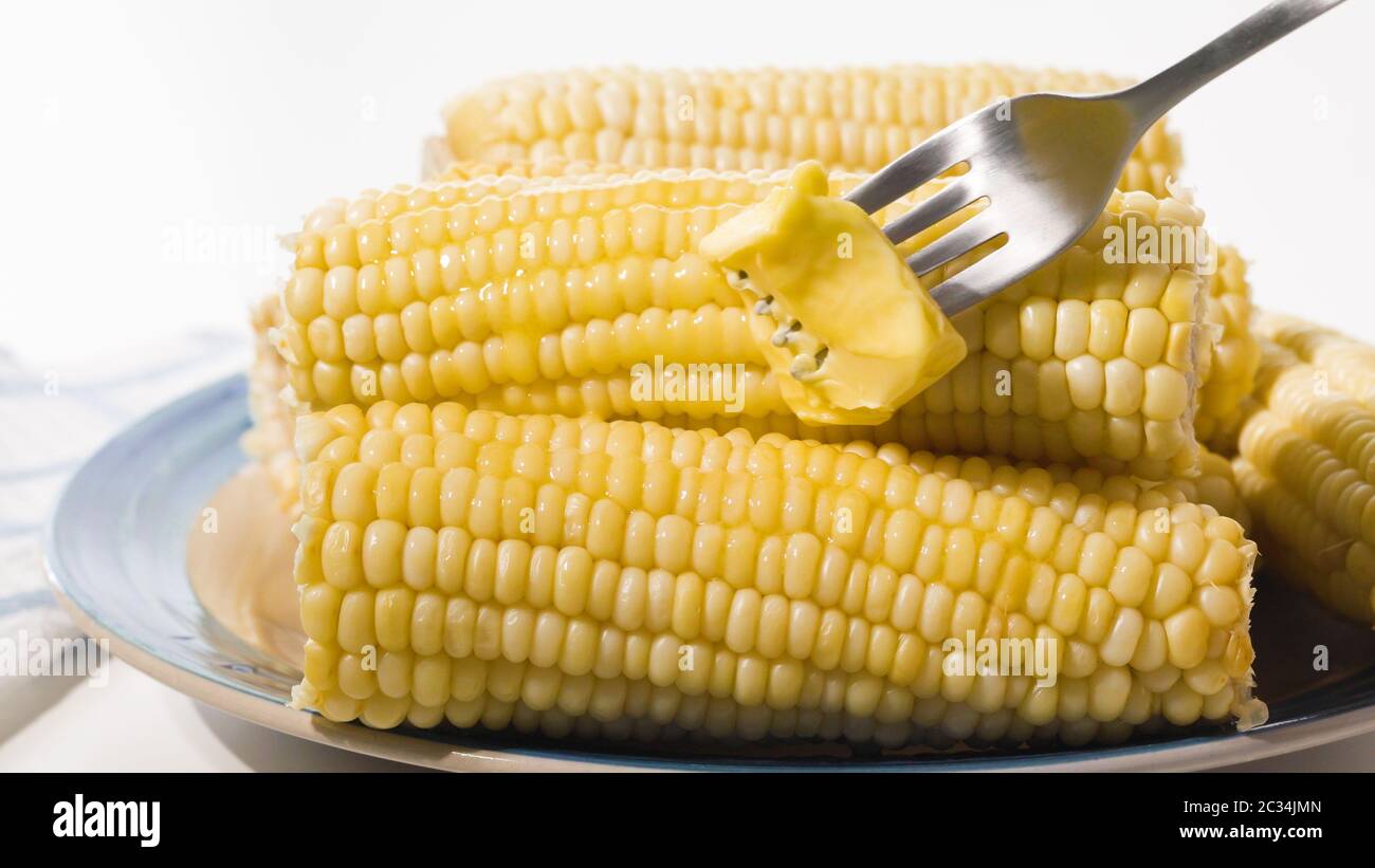 White corn. Boiled sweet white corn with butter close up on a plate on ...