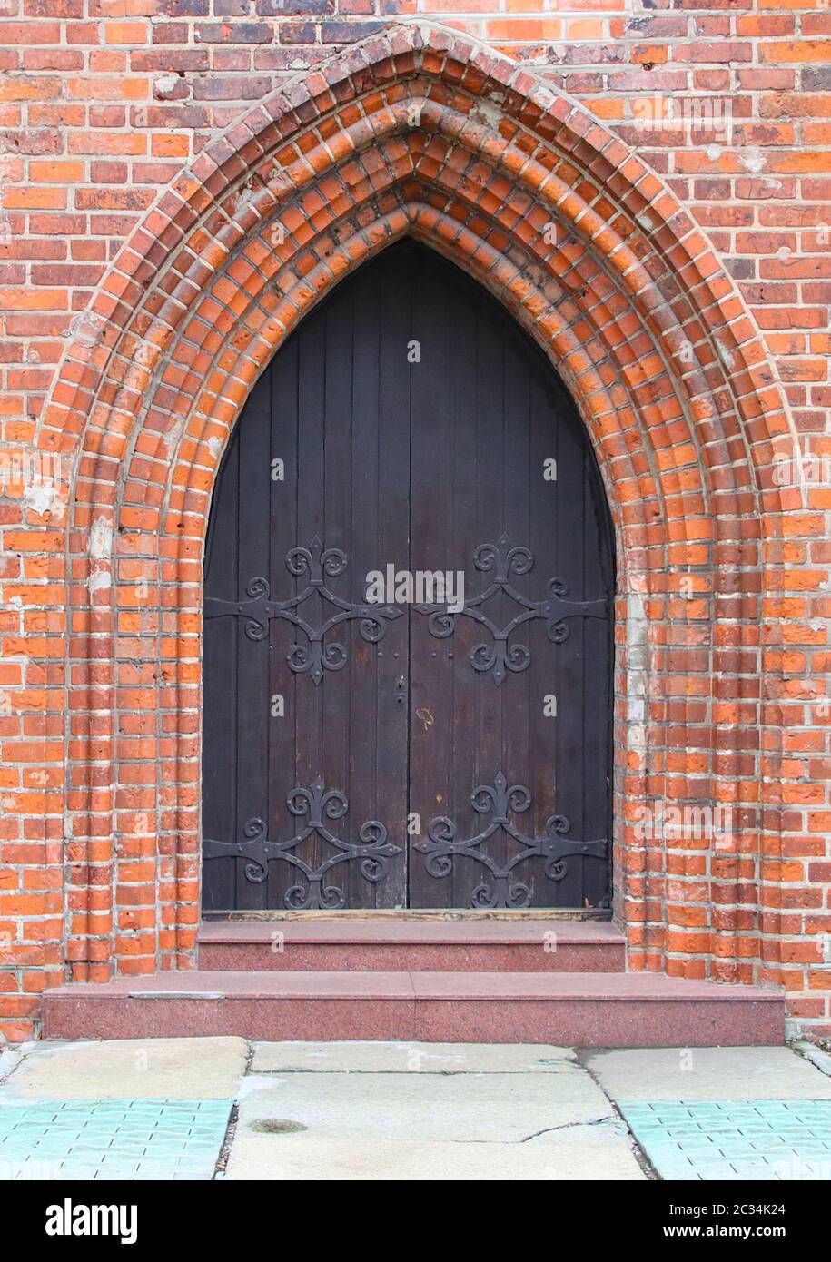 Medieval Gothic brick arch over a metal door Stock Photo - Alamy