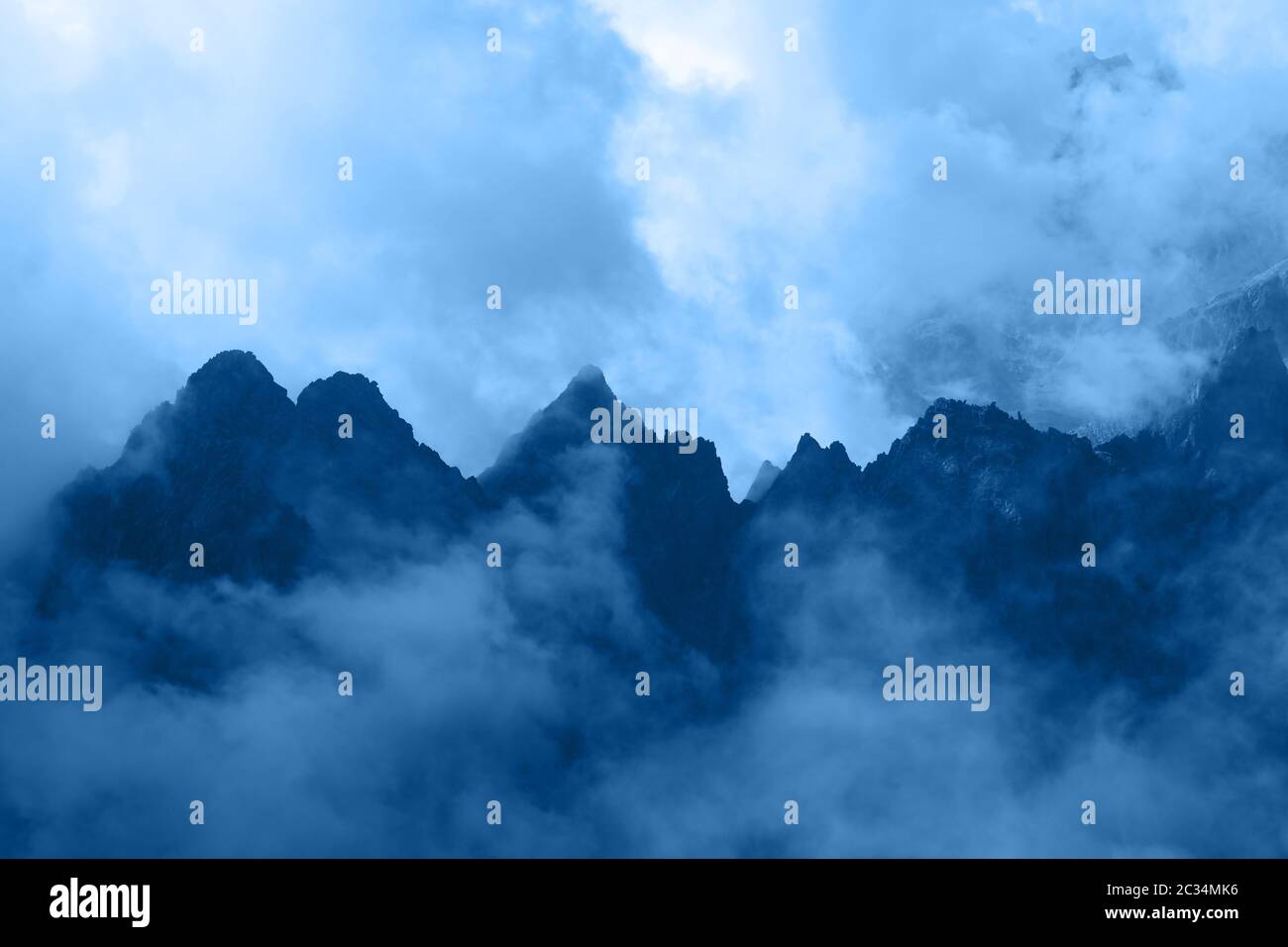 Blue toned landscape of dark rocky mountain ridge silhouette in foggy ...