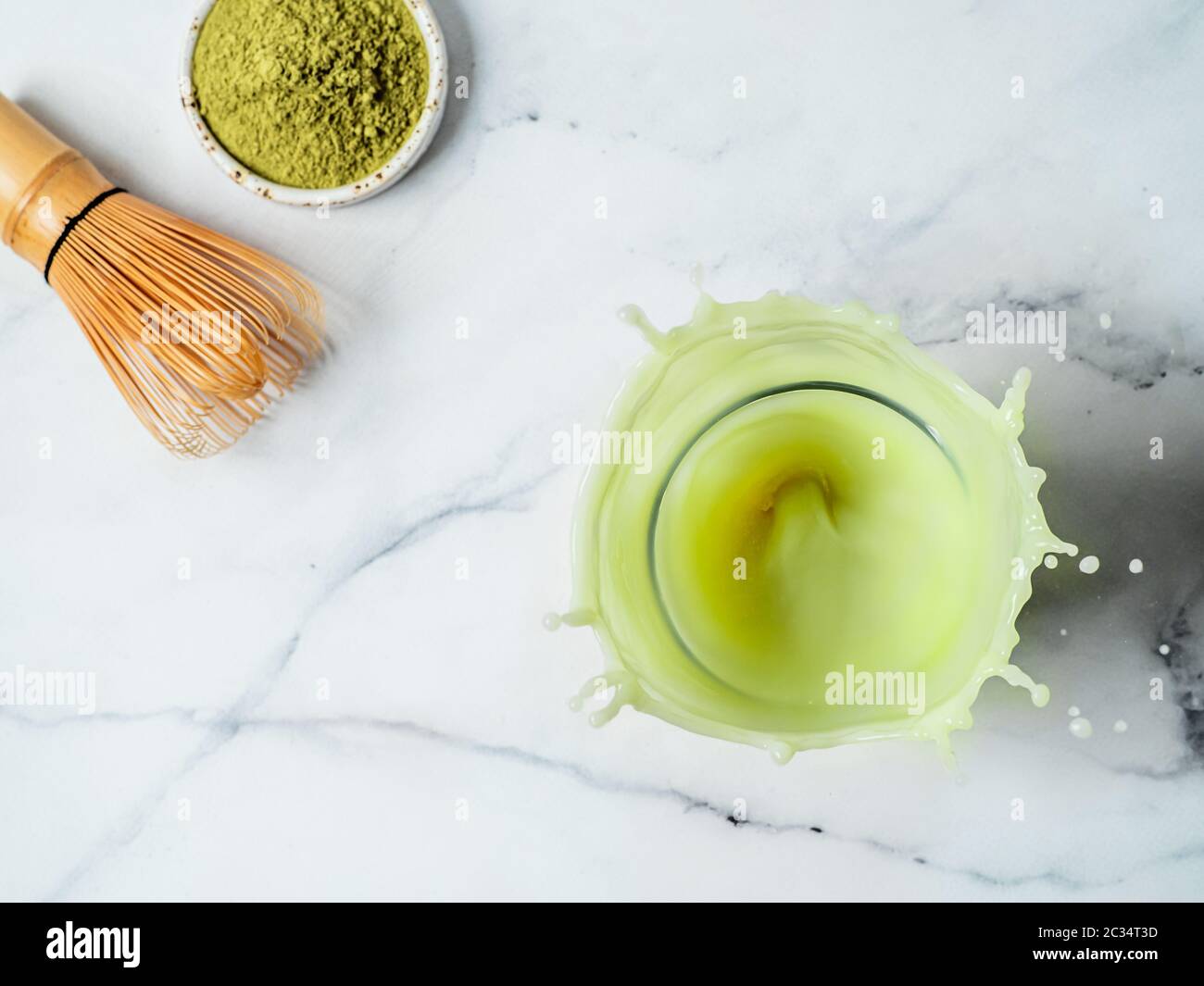 Homemade iced matcha latte with splashes over white marble background ...