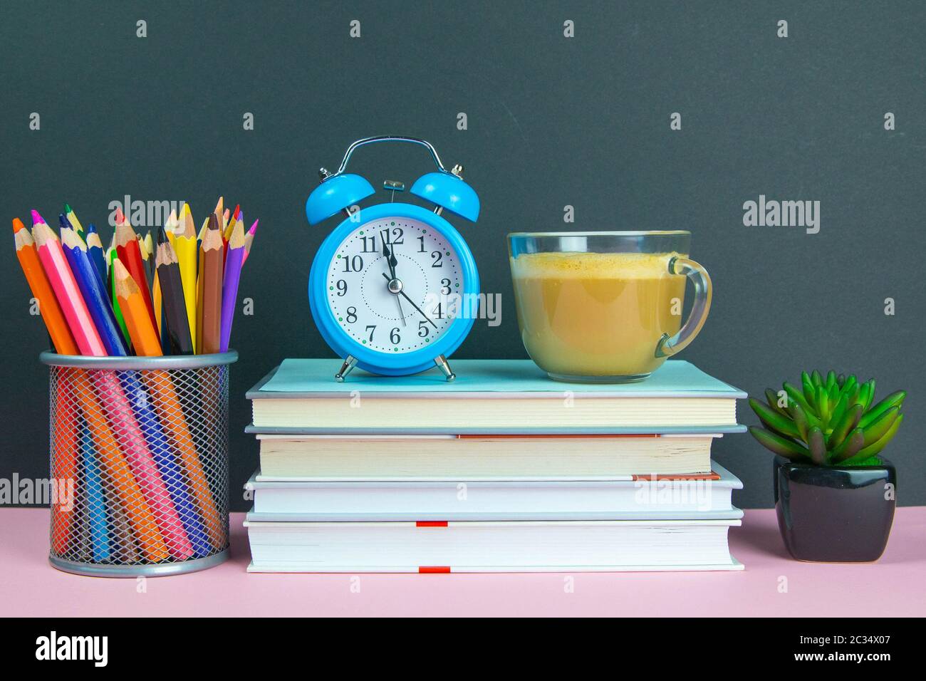 A stack of books on which stands a coffe with milk next to stands a ...