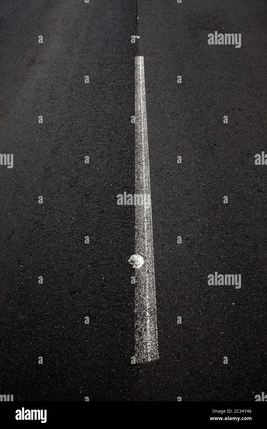 white road markings defining the order of traffic on the asphalt road ...