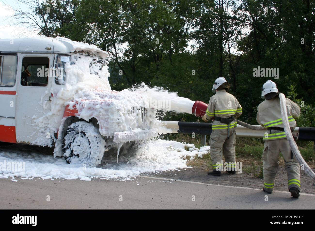 firefighters with foam extinguish a burning bus Stock Photo - Alamy