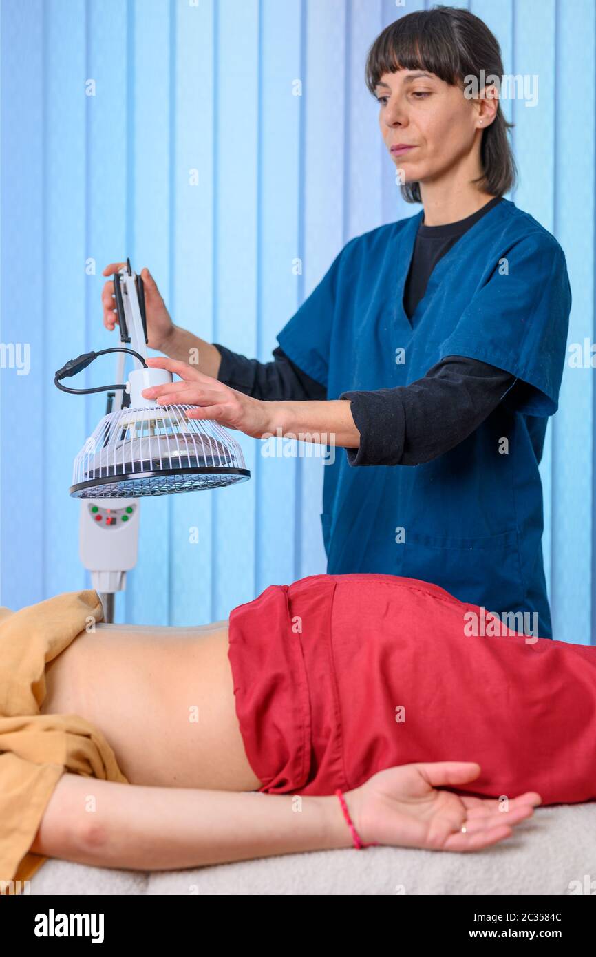 Therapist doing healing infrared treatment on woman back . Alternative ...
