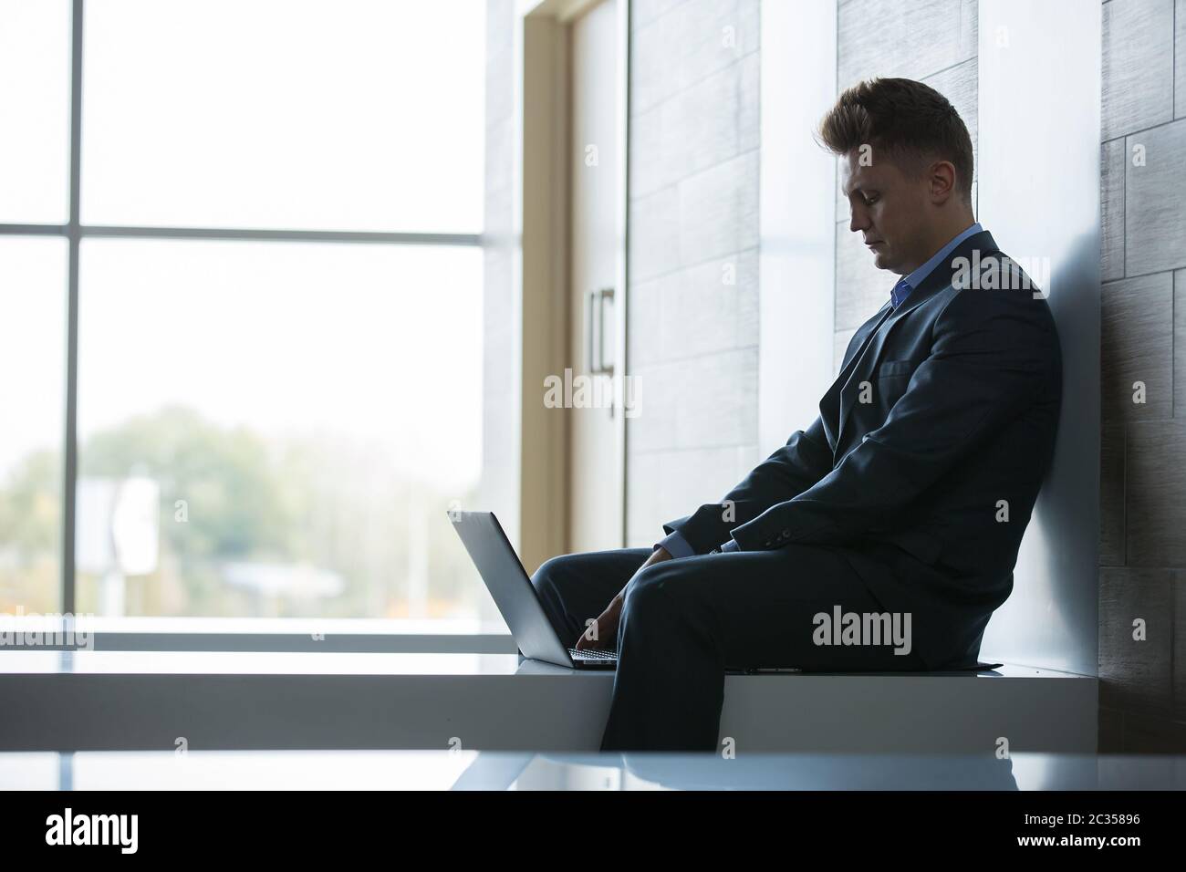 Business man sitting alone on a bench with laptop Stock Photo - Alamy