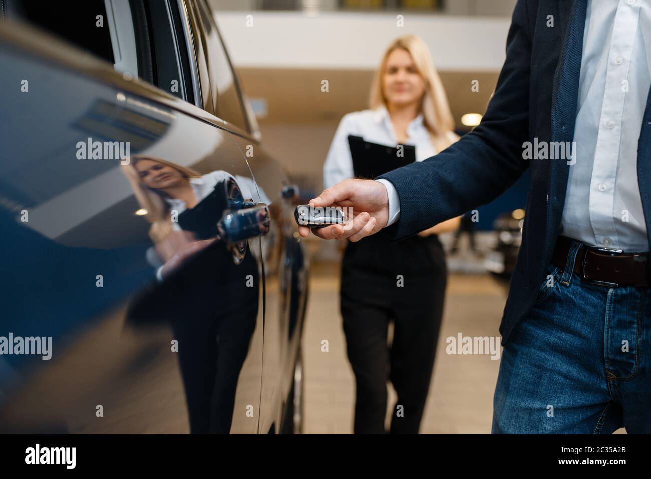 Man and saleswoman choosing auto in car dealership. Customer and seller ...