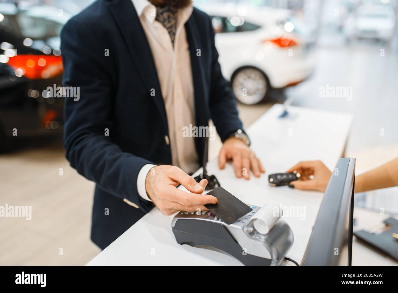 Man pays for the purchase of a new auto in car dealership. Customer and ...