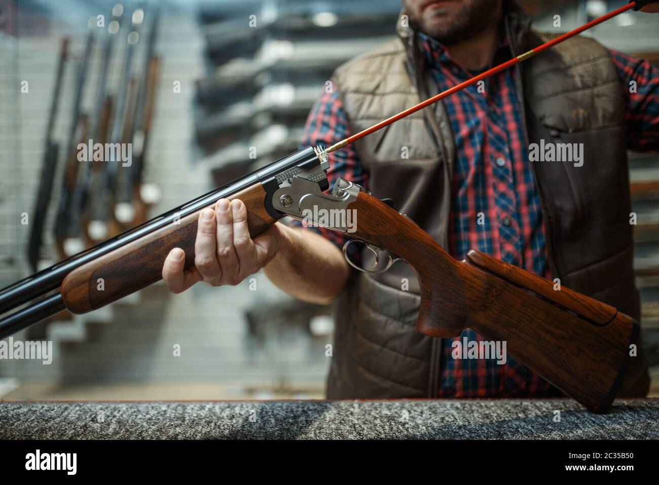Man cleans rifle barrel at counter in gun shop. Euqipment for hunters ...
