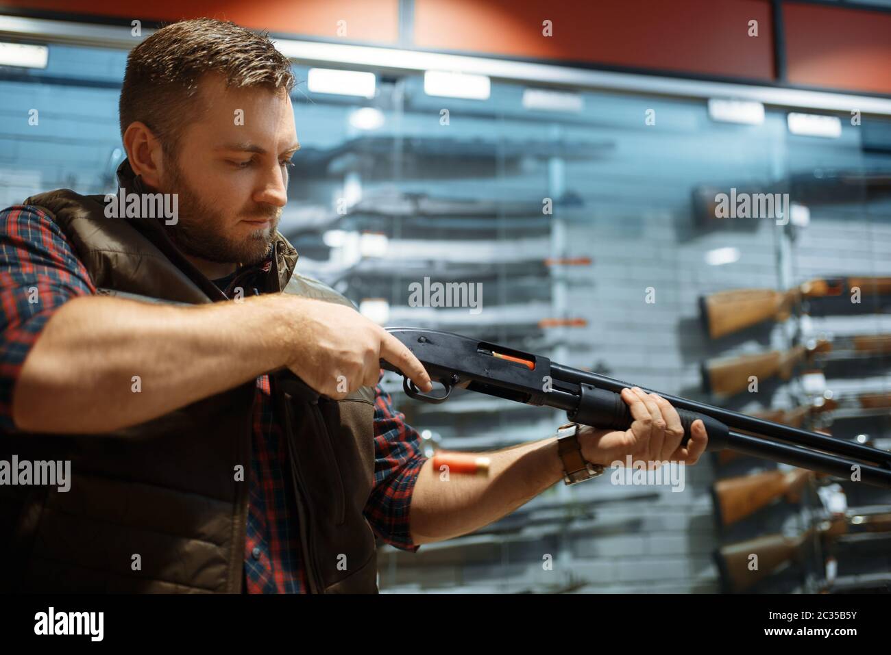 Man loads new rifle at counter in gun shop. Euqipment for hunters on ...
