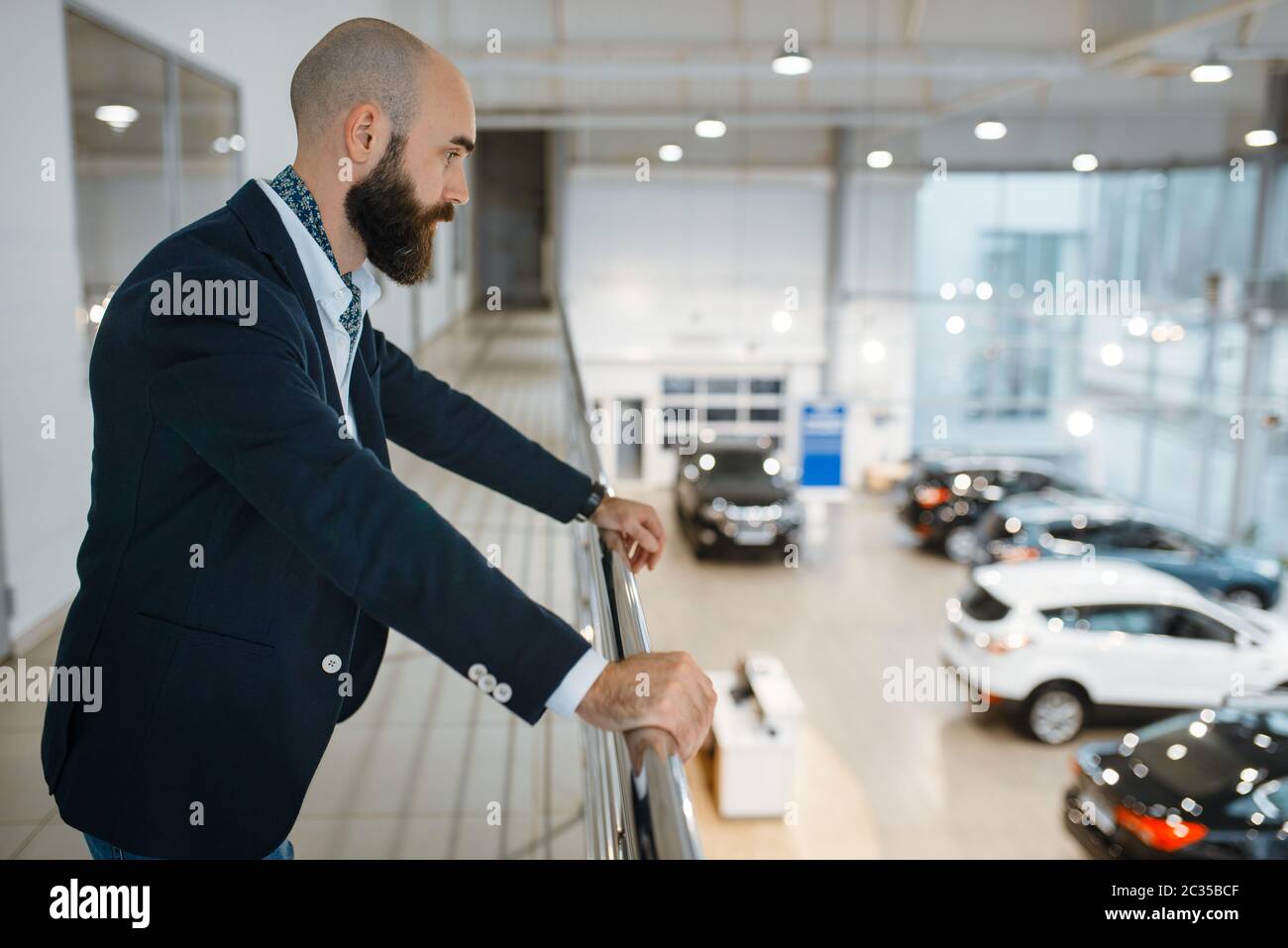 Happy businessman poses in car dealership. Customer in new vehicle ...