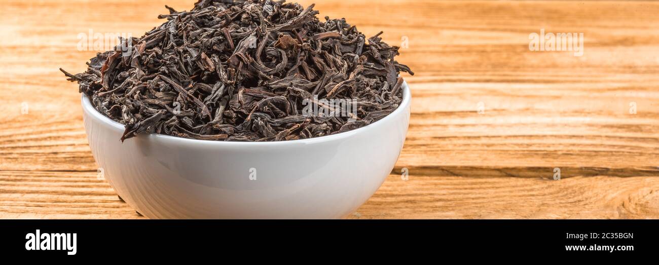 Dried tea is poured into a ceramic cup on a wooden plank table Stock ...