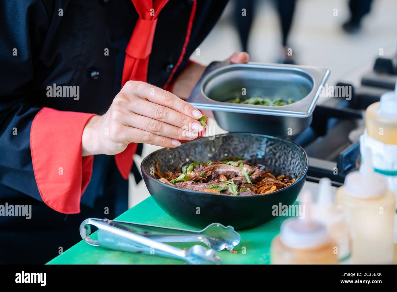 A female using tongs to grab noodles out of a frying pan Stock Photo ...