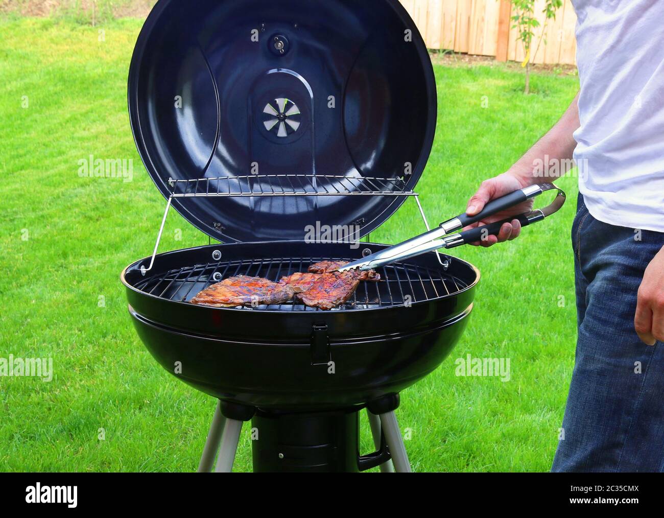 Man roasting beef on BBQ grill Stock Photo - Alamy