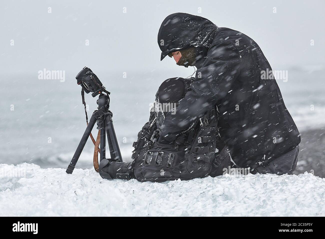 Photographer changing lens in challenging conditions in a snow storm ...