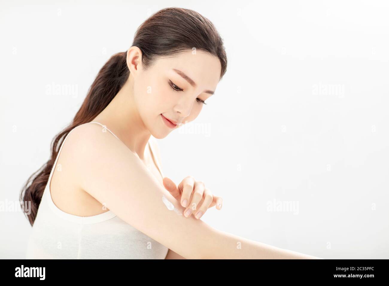 Beautiful young woman applying body lotion Stock Photo - Alamy