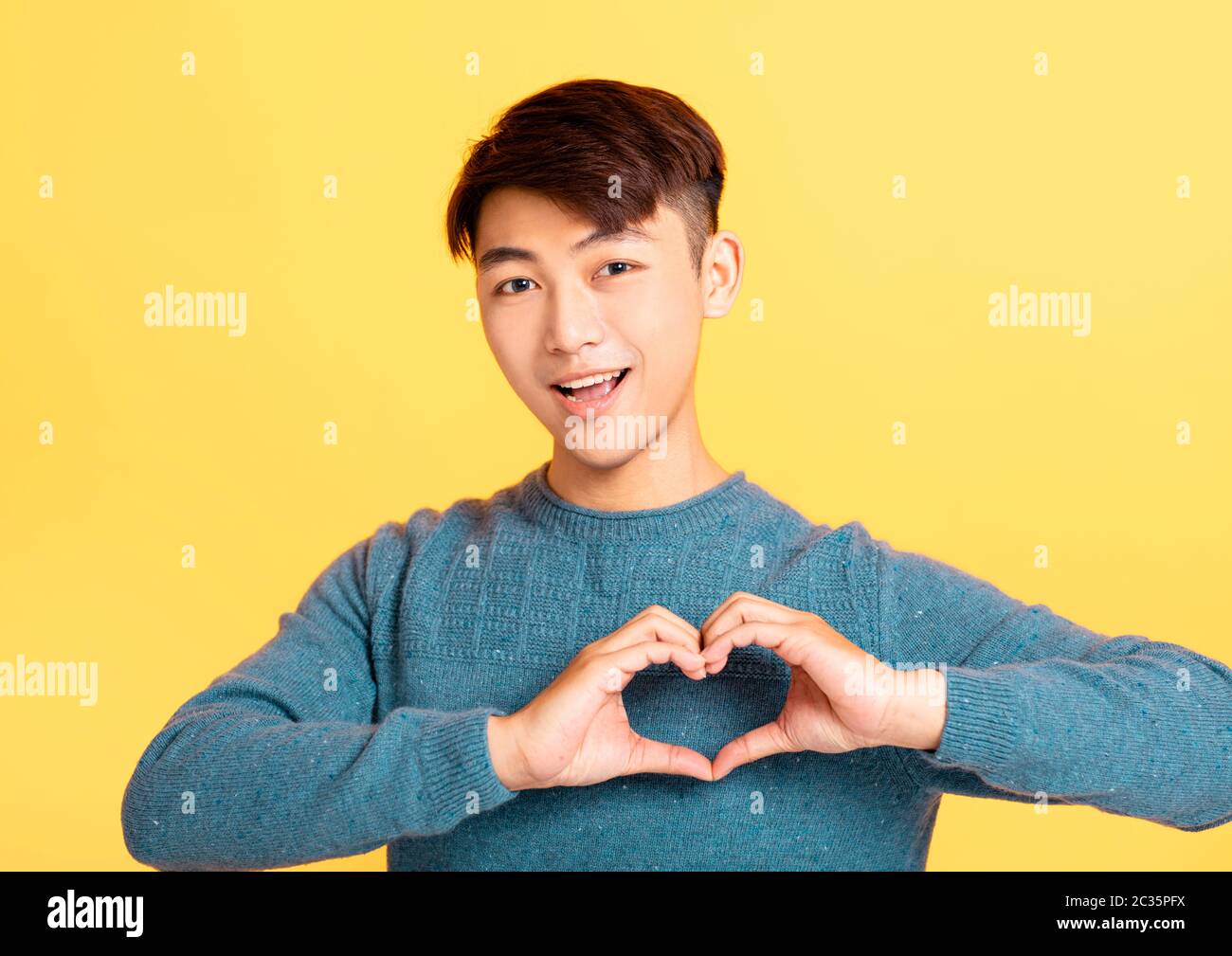 young Man showing hand sign heart on his chest Stock Photo - Alamy