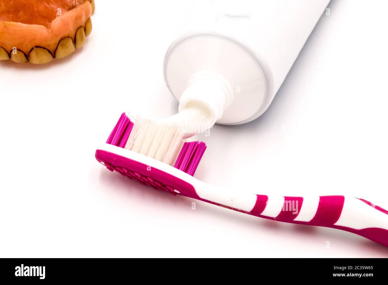 Toothpaste on a toothbrush with a dirty denture on a white background ...