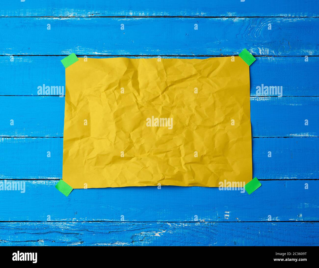 empty yellow crumpled sheet of paper glued with green sticky pieces of ...