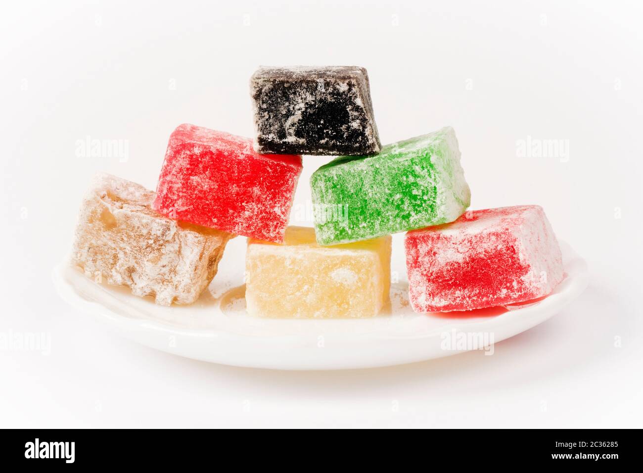 Different colorful Turkish delight cubes are on plate on white ...