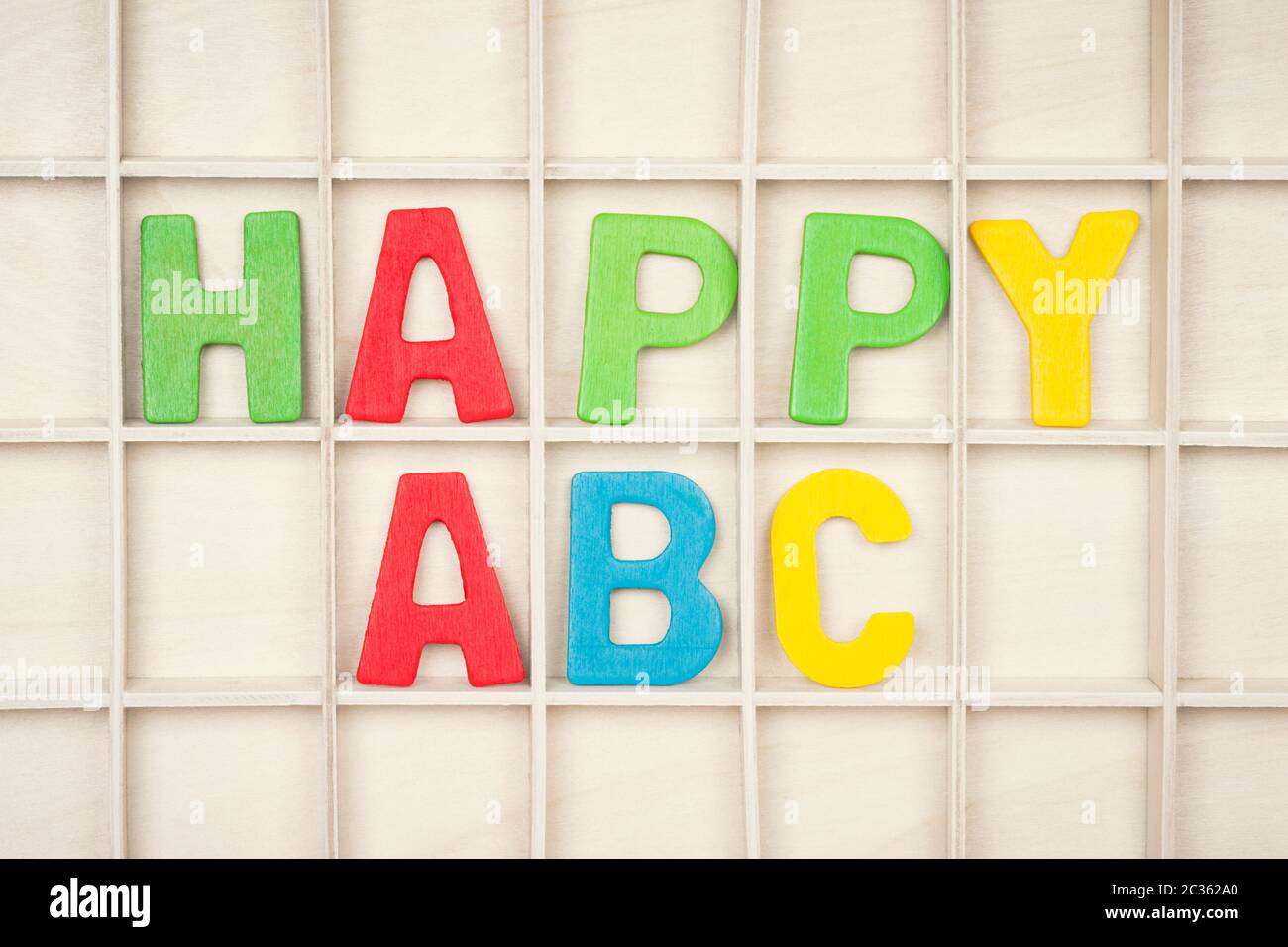 The HAPPY ABC text from colorful wooden letters is on wooden background ...