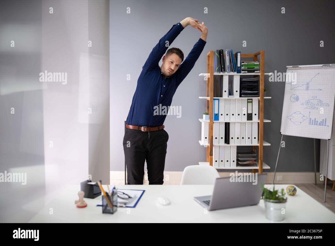 Young Businessman Stretching At Workplace In Office Stock Photo - Alamy