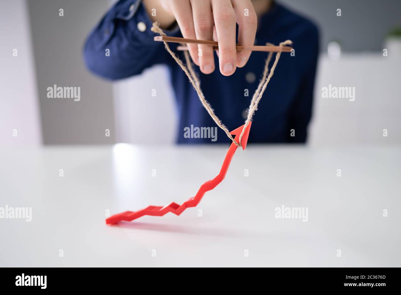 Businessperson's Hand Manipulating Red Arrow With Rope Stock Photo - Alamy