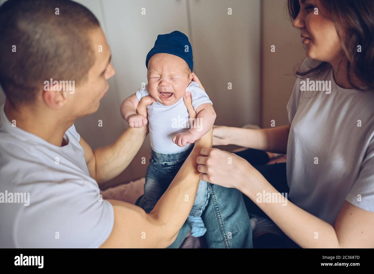 Close up portrait of a happy parents holding their crying baby. Young ...