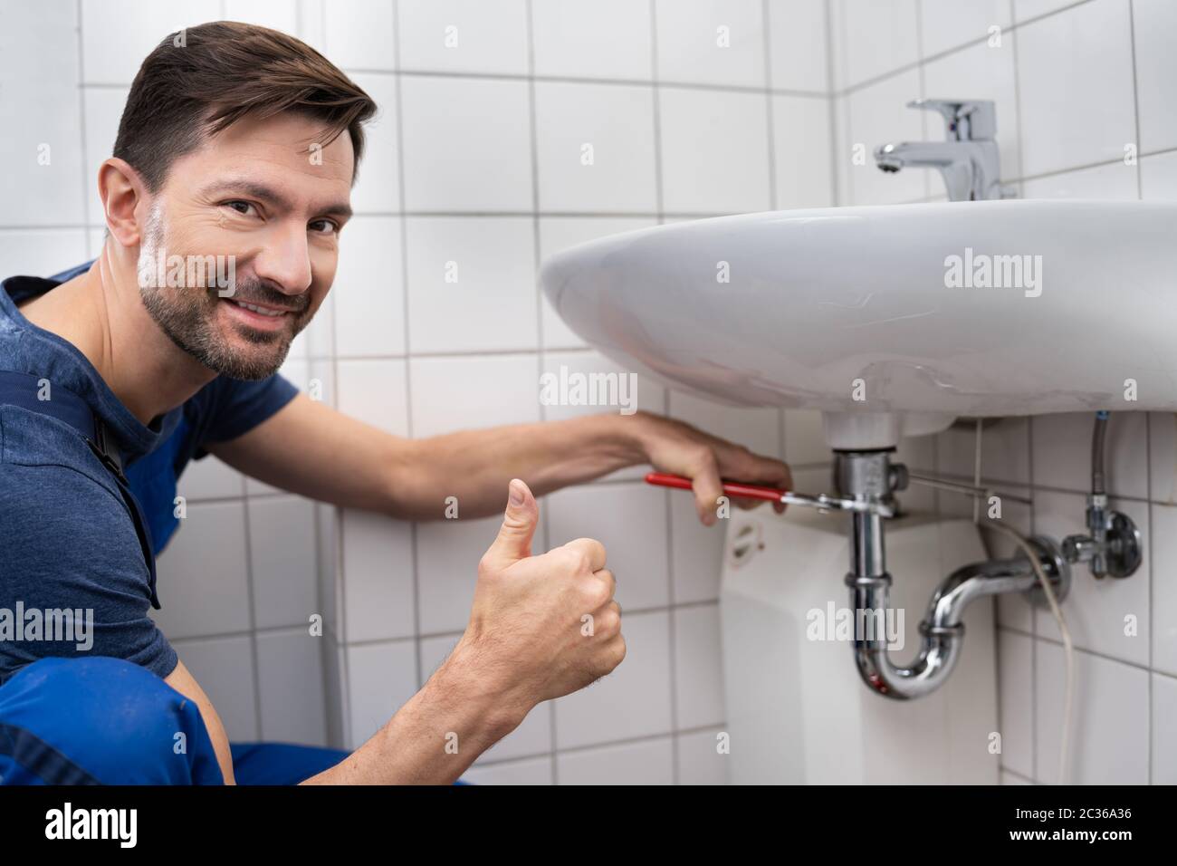 Young Plumber Fixing A Sink In Bathroom Stock Photo - Alamy