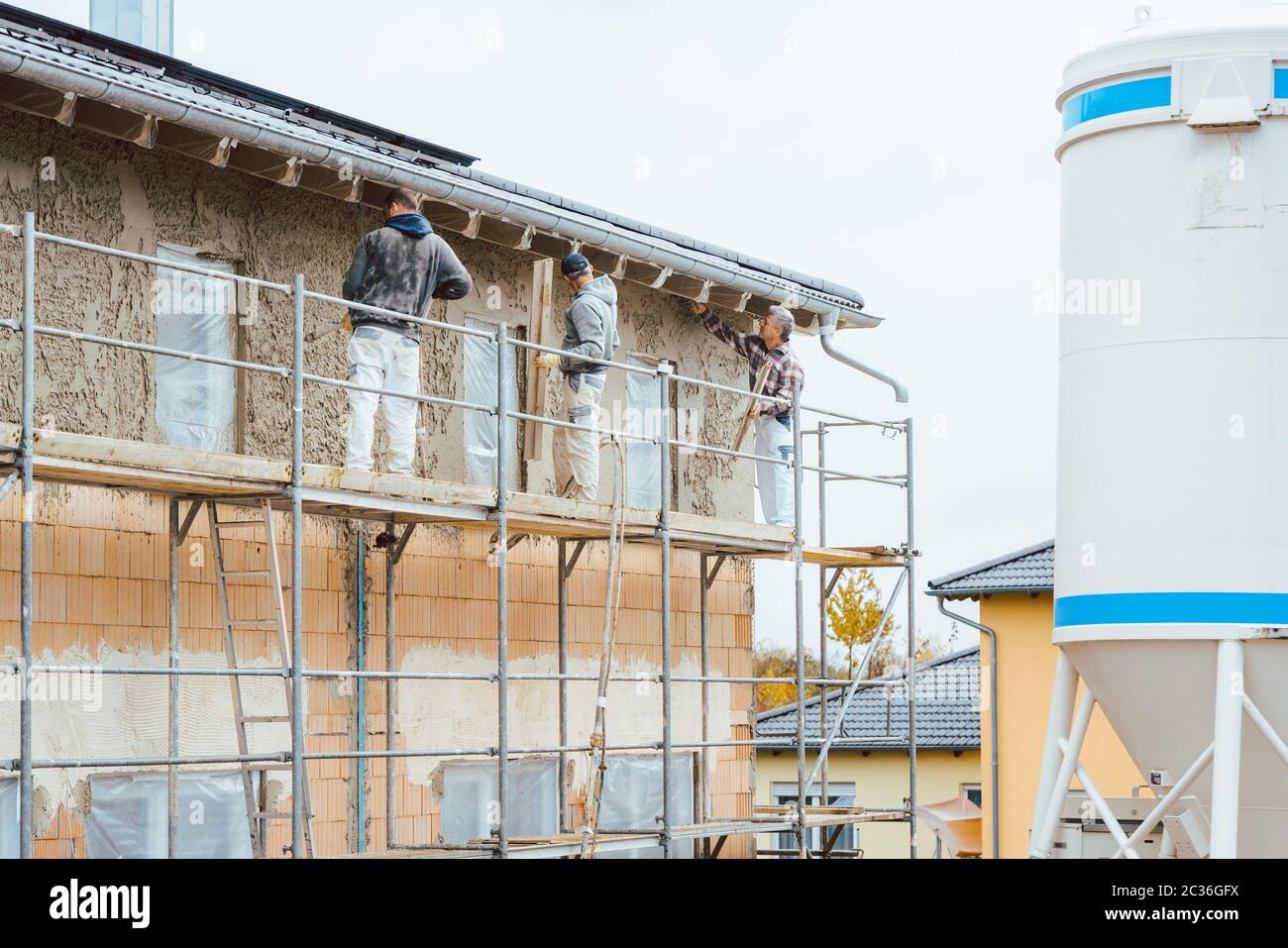 Plaster worker on scaffold working on outer wall of house Stock Photo ...