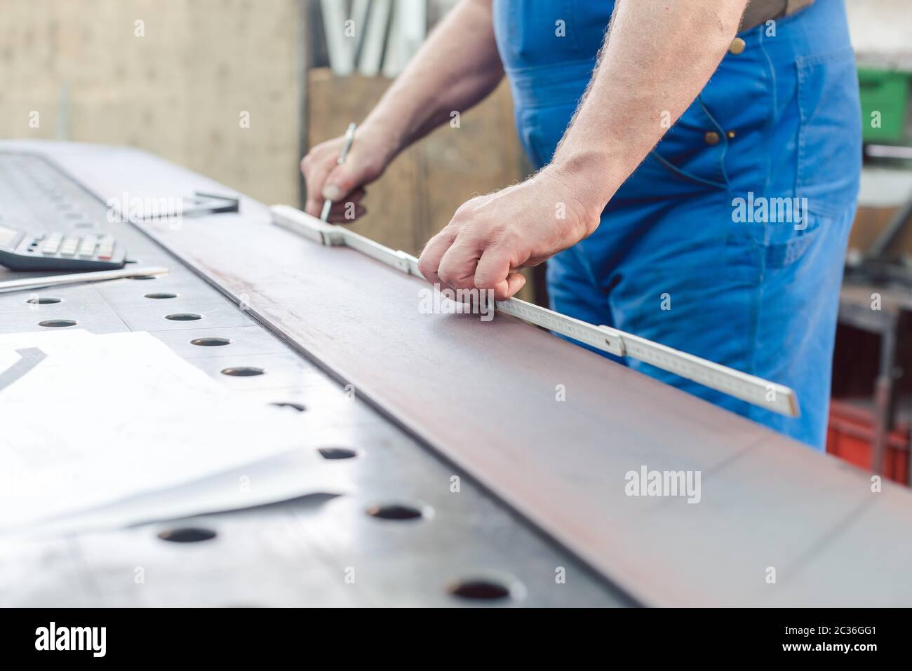 Metalworker using folding rule to measure steel strip for later cutting ...