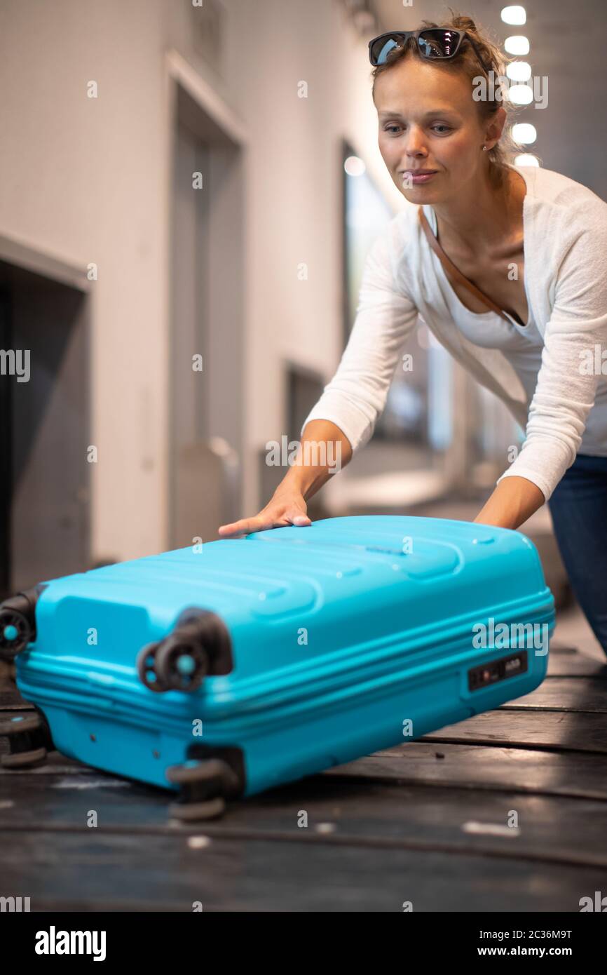 Young woman with her luggage at an international airport, waiting for ...