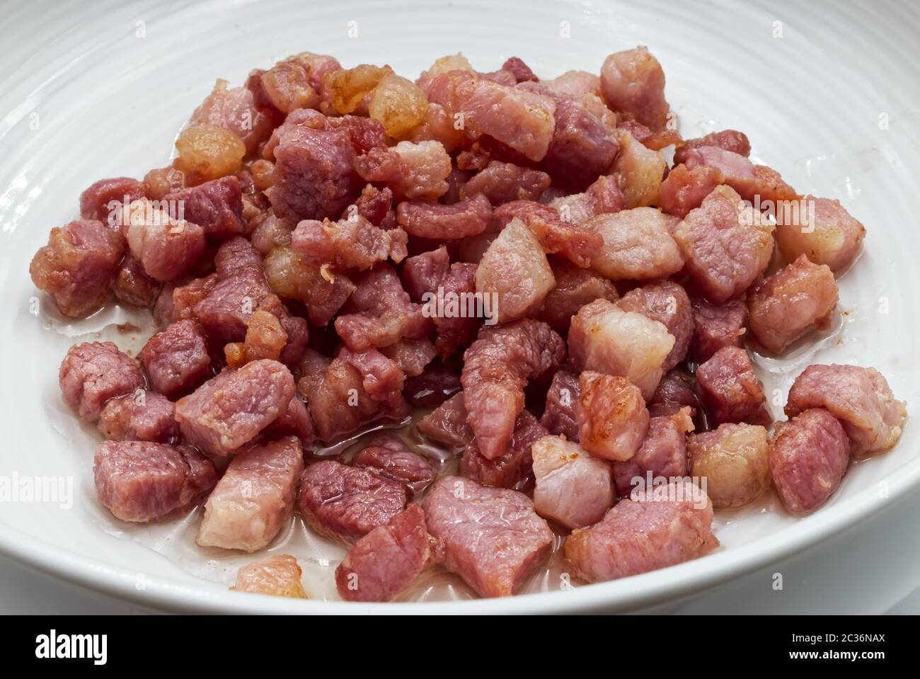 Bacon cubes in ceramic bowl, isolated on white background Stock Photo ...
