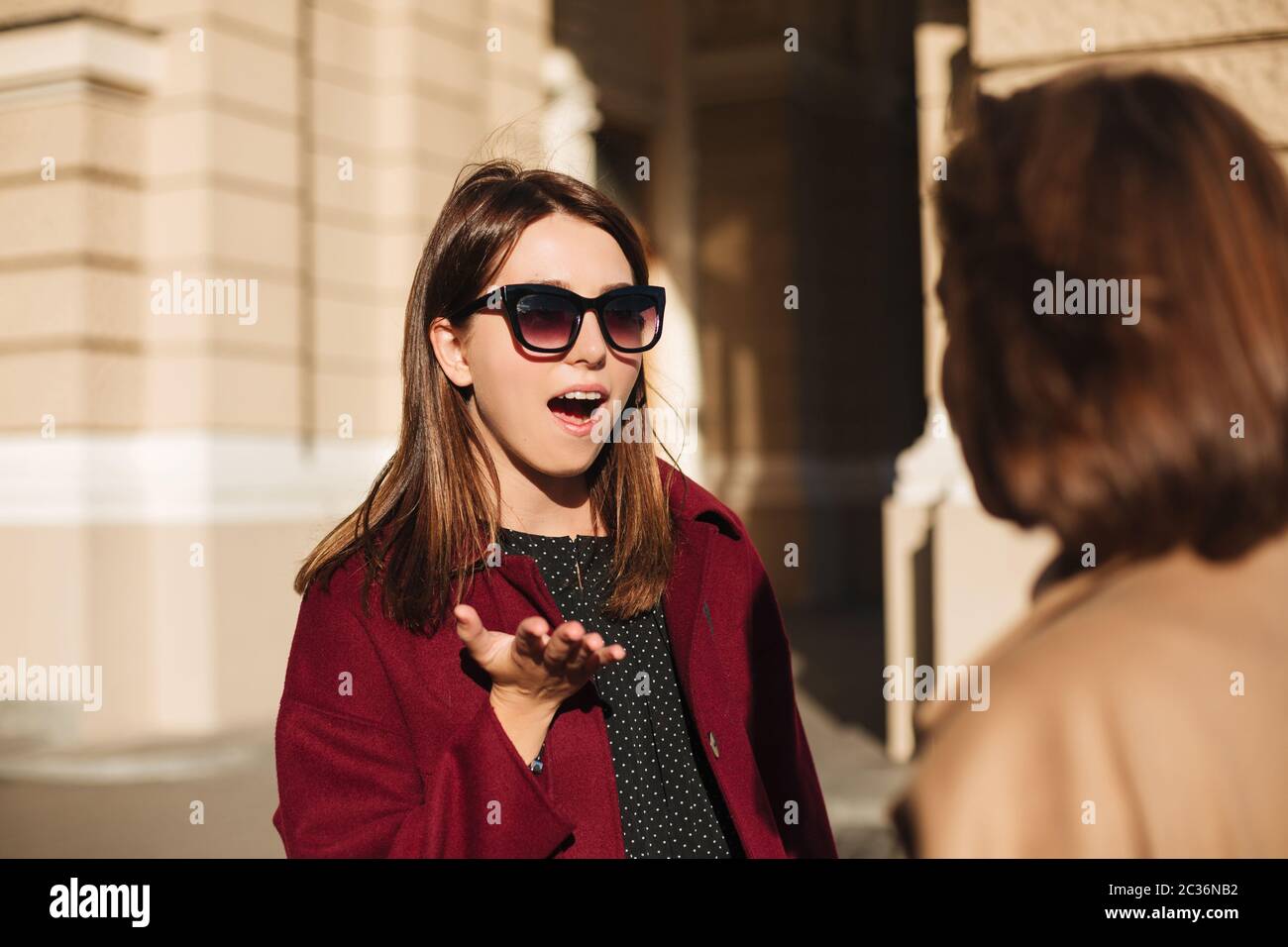 Portrait of young lady in sunglasses standing and amazedly looking at ...