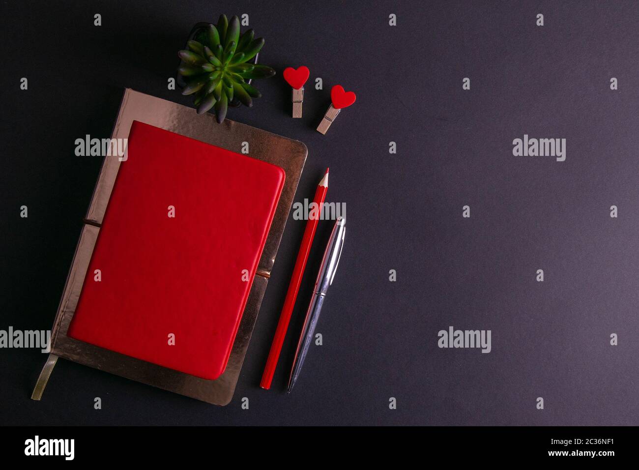 The red notebook stands on a gold notebook which stands on a black ...