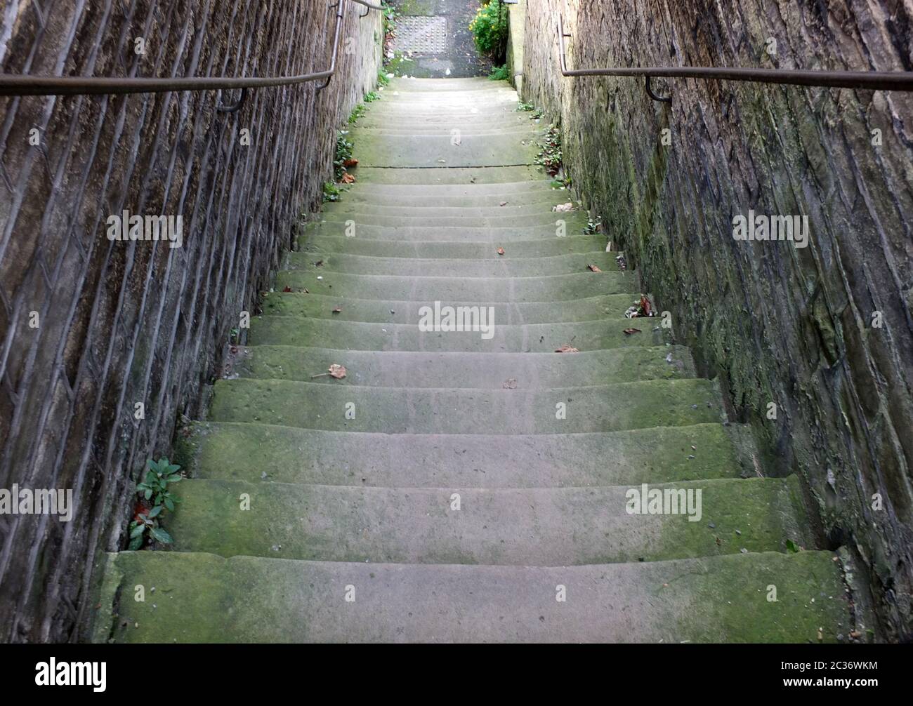 a perspective view of narrow old outdoor stone steps descending between ...