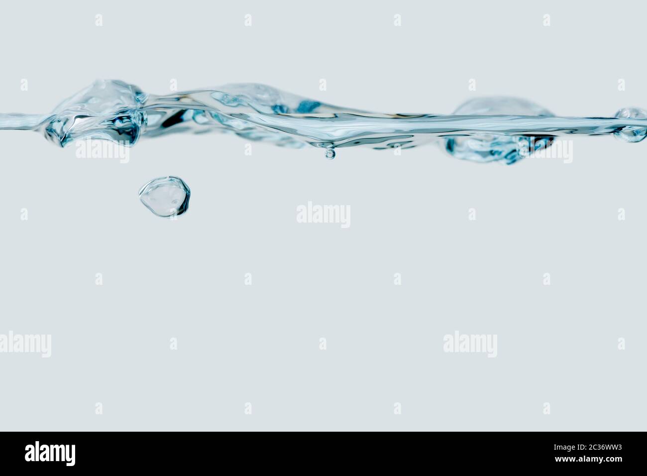 Studio shot of a small water wave with a single rising bubble against ...