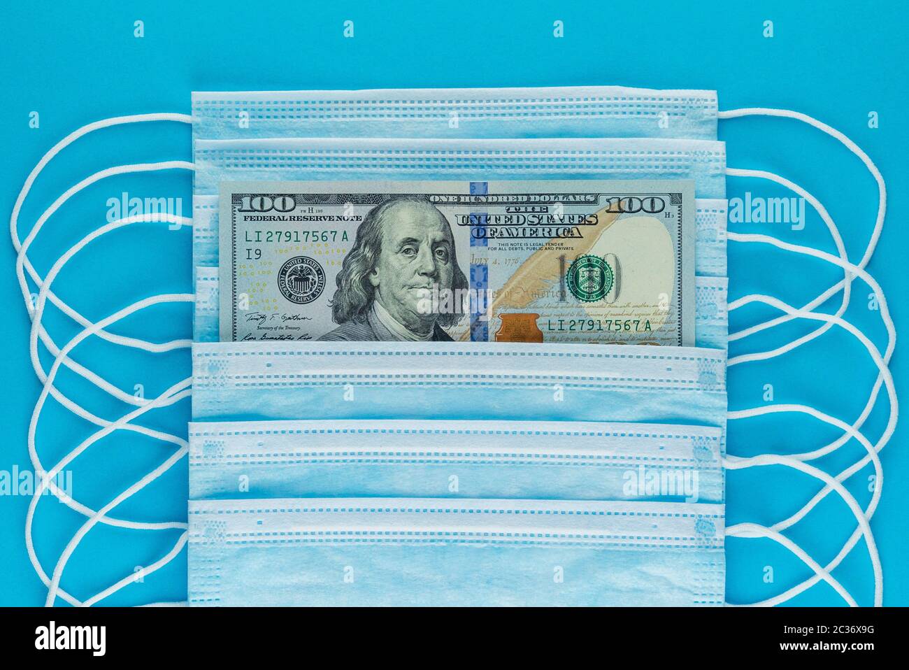 Blue medical masks, and american money, flat lay. 100 dollar bill in a ...